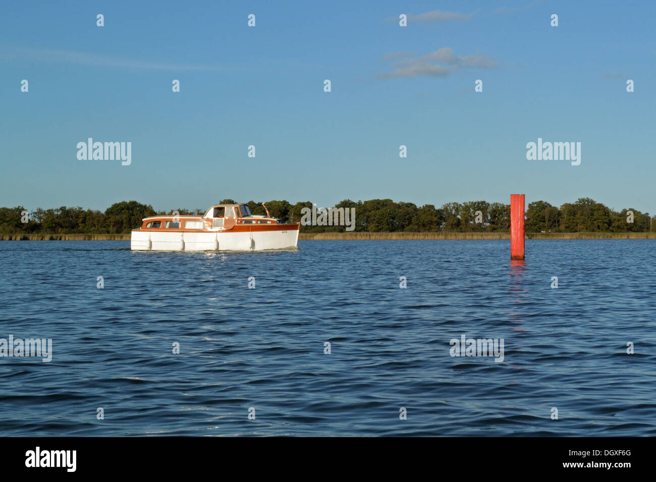Traditional wooden Broads cruiser approaching a navigation marker post ...