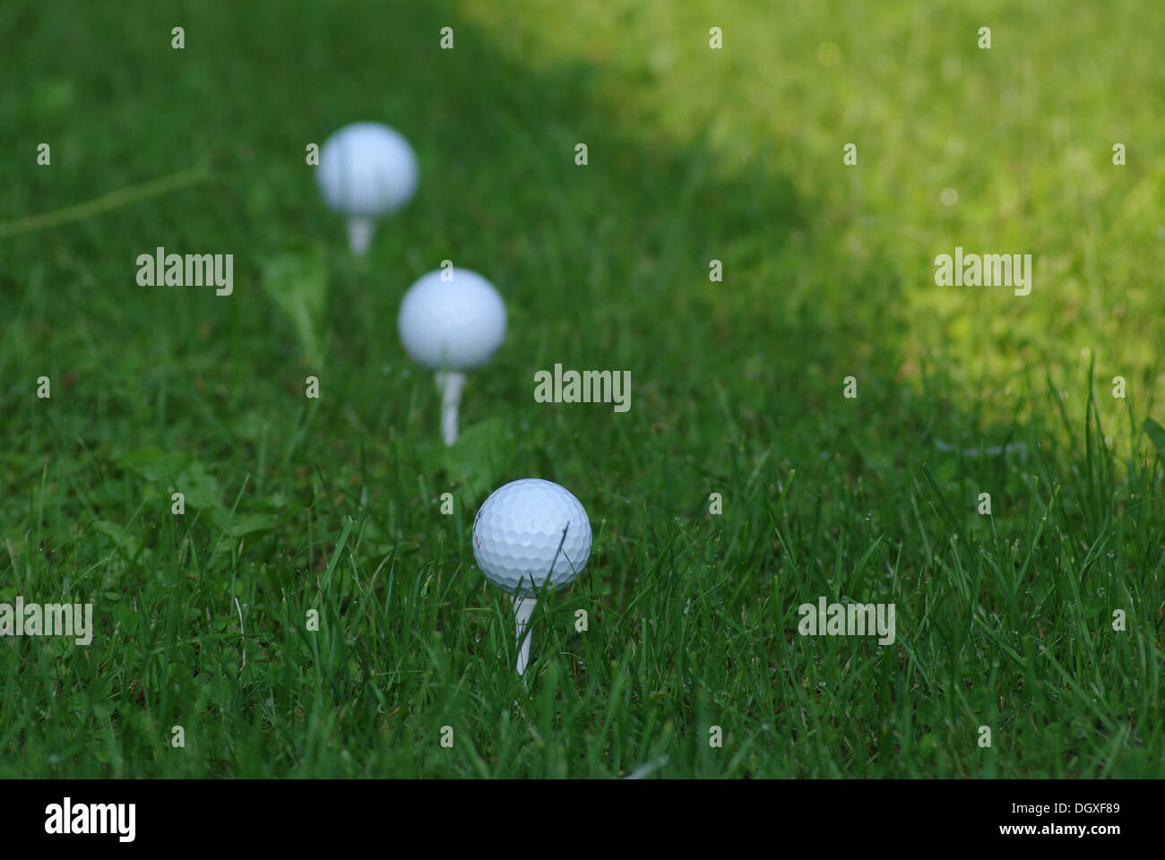 three golf balls in line on grass Stock Photo - Alamy