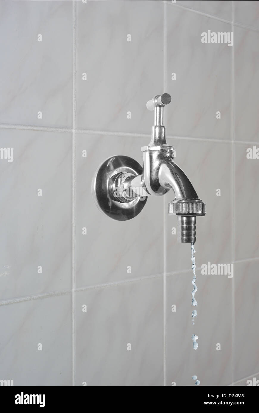 dripping metal tap on tile background Stock Photo - Alamy