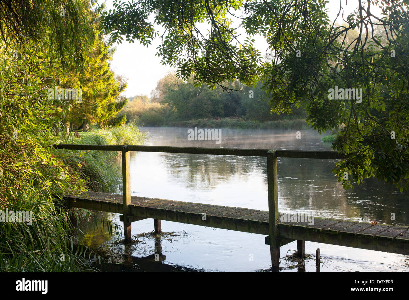 Footbridge over the water as early morning sunshine reflects on the ...