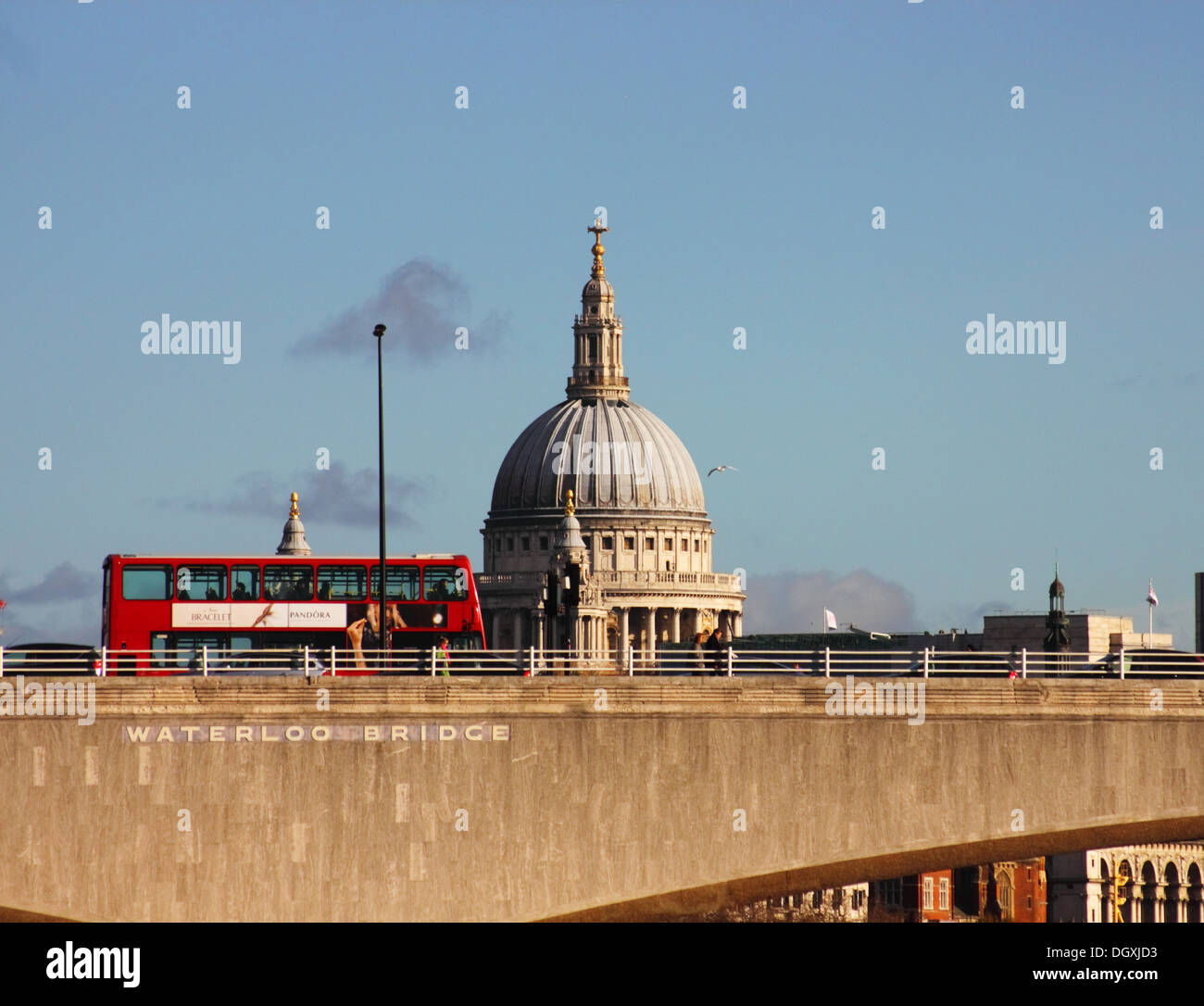 A red double decker London bus crosses Waterloo Bridge with the dome of ...