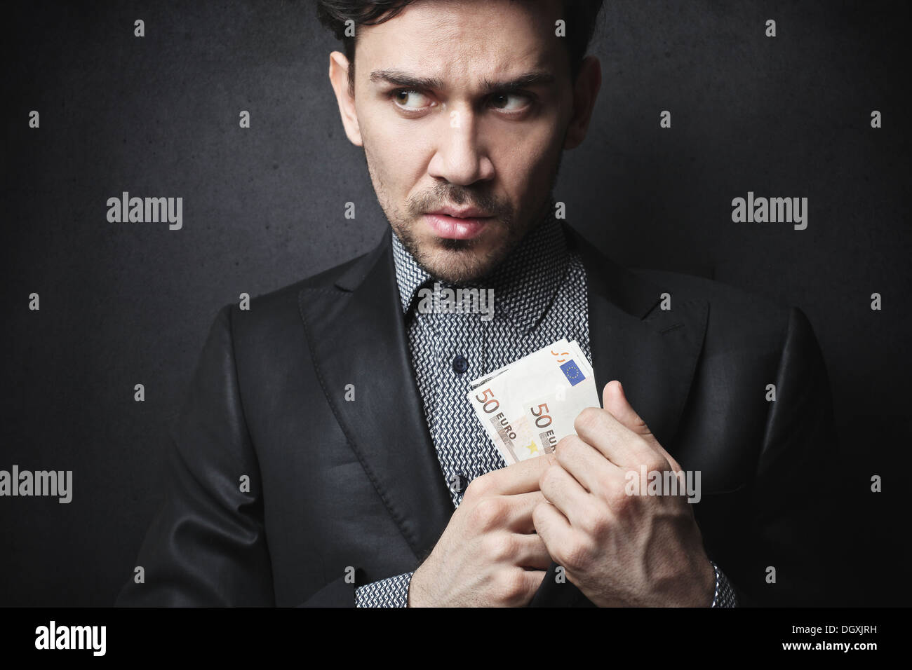Elegant man hiding fifty euro banknotes in his suit jacket Stock Photo ...