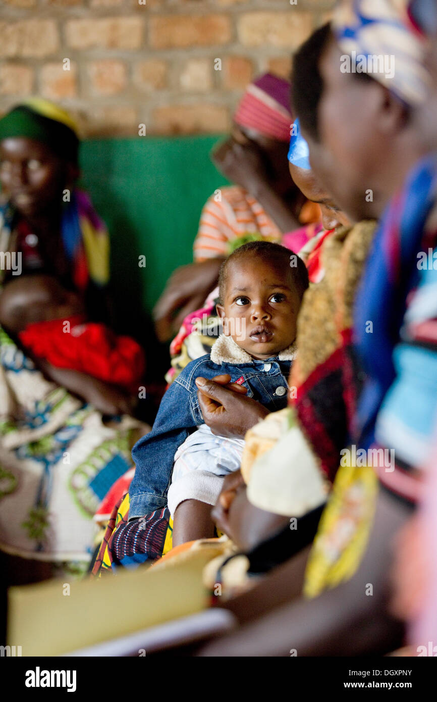 Parents and their children wait outside a health center in Rukogo near ...