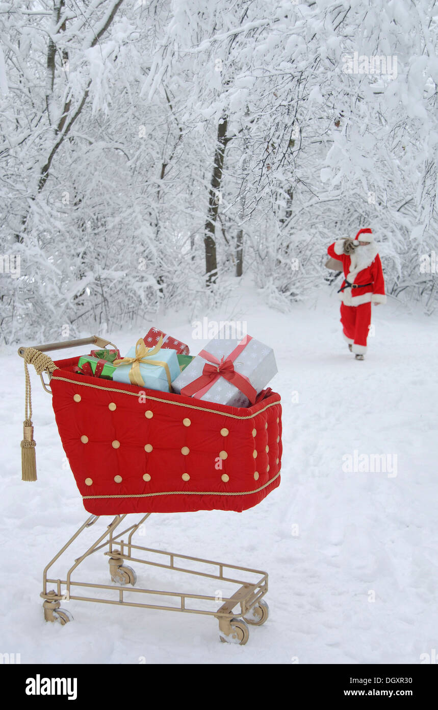 Santa Claus in a snowy forest with a shopping cart with red velvet and ...
