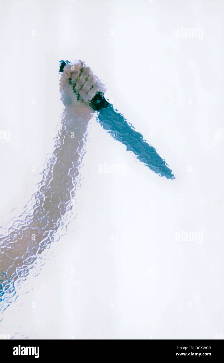 Raised hand holding a large butcher's knife behind cathedral glass ...