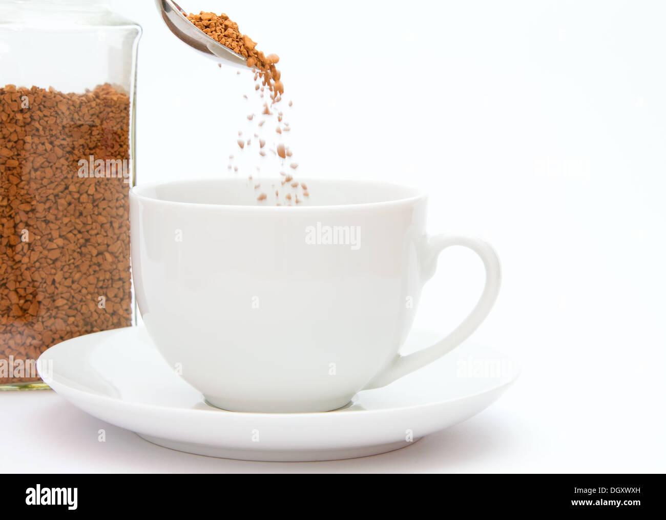 Spoon of coffee granules dropping into cup Stock Photo - Alamy