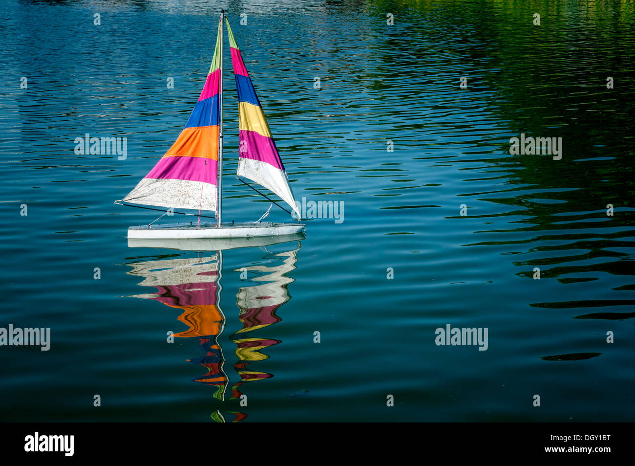 Scale model of a sloop sail boat with multi-colored striped sails ...