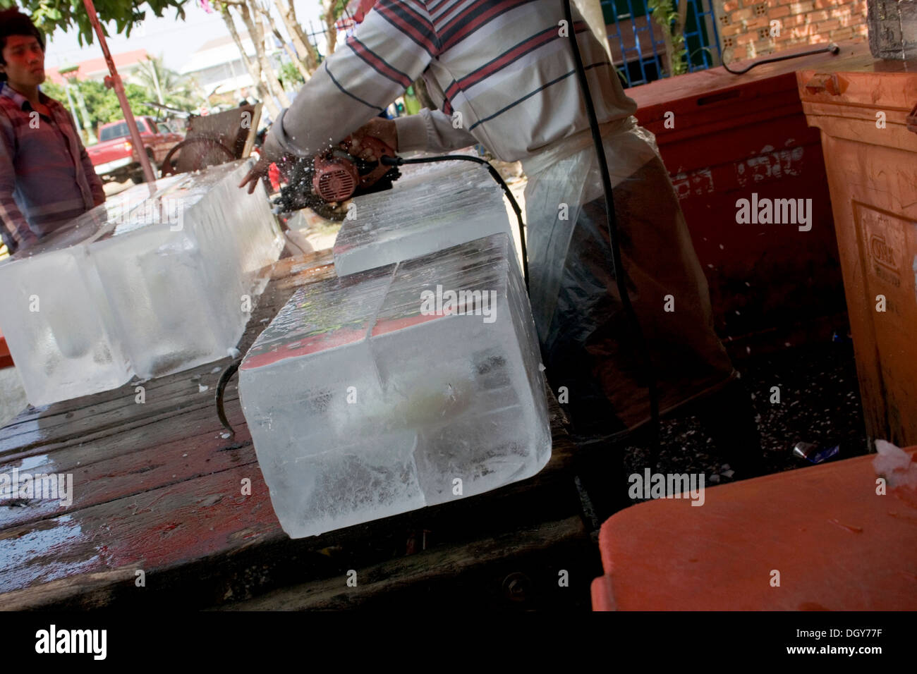 A man is cutting a large ice block with a circular saw in an ice ...