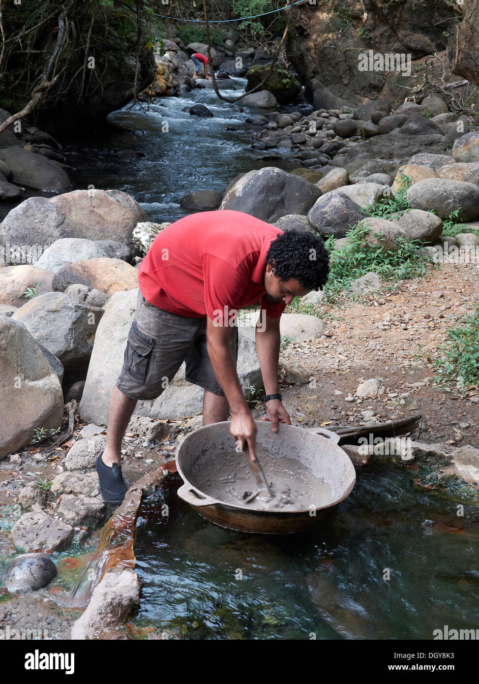 Man stirring volcanic mineral mud, Ricòn de la Vieja National Park ...