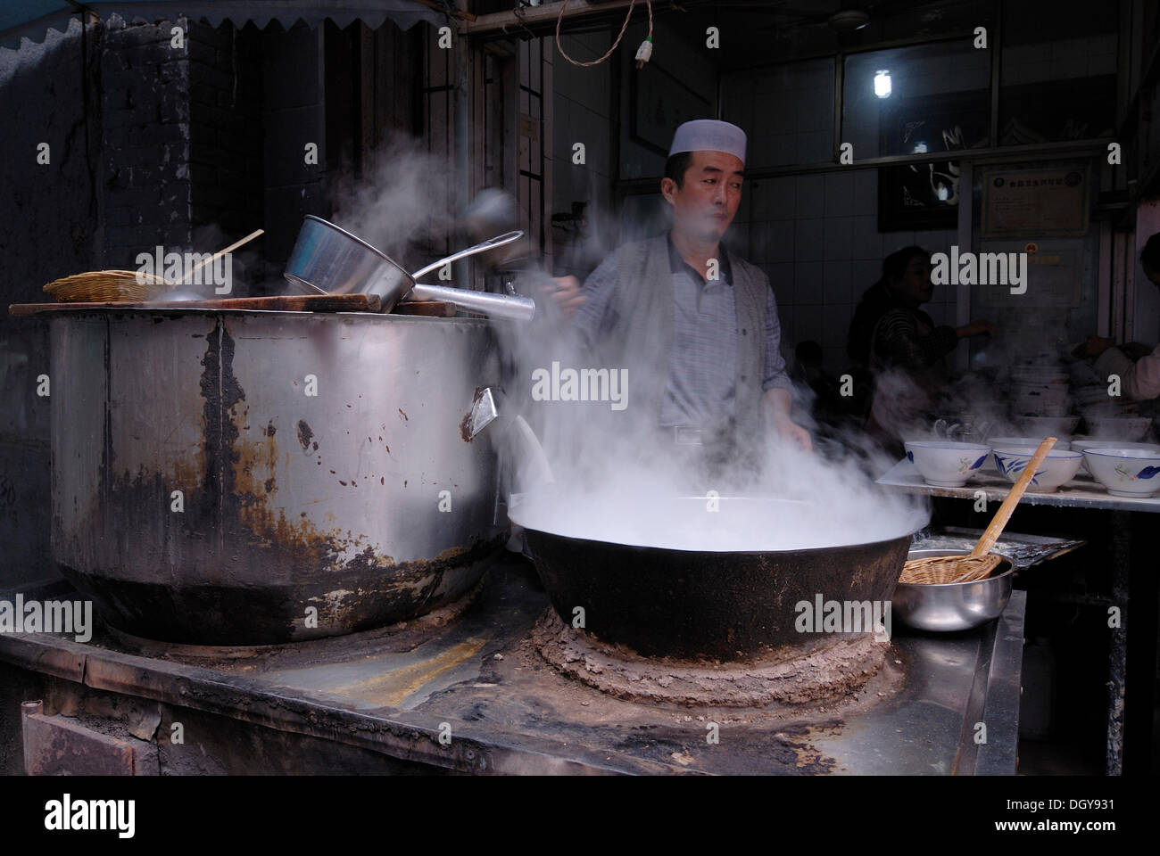 Muslim noodle cookshop with Muslim cook and large steaming pots on an ...