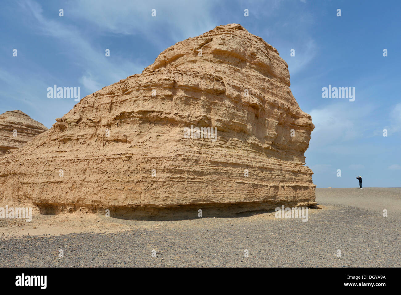 Tourist standing in a dry stony desert landscape with rock formations ...