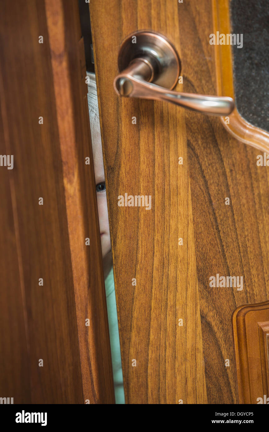 Girl peeking through front door Stock Photo - Alamy