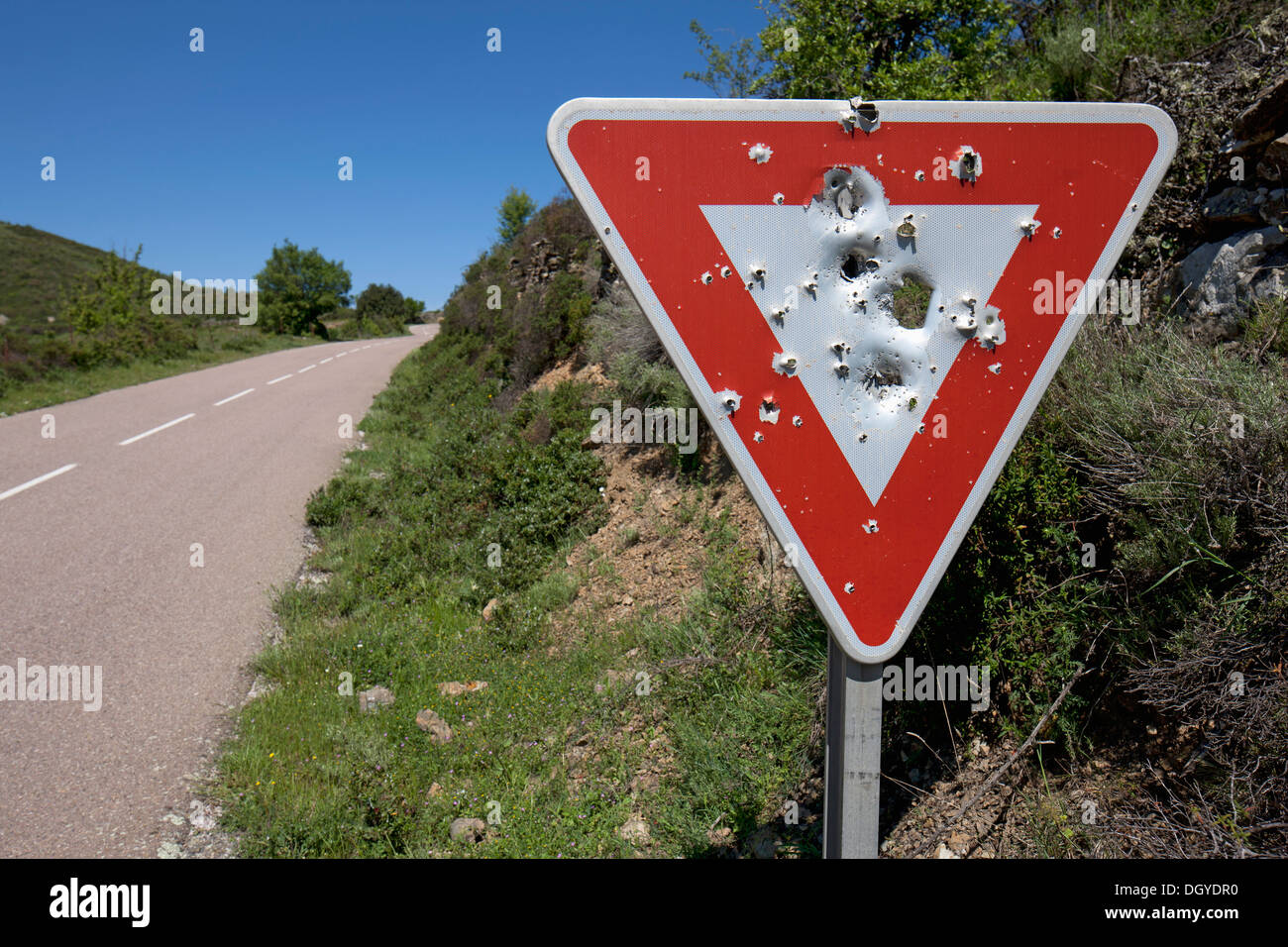A yield sign with bullet holes in it posted on a remote highway Stock ...