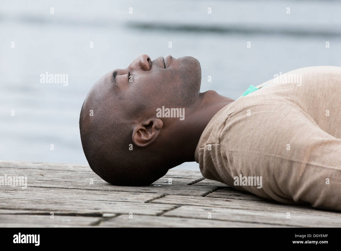 Man napping on decking by lake Stock Photo - Alamy