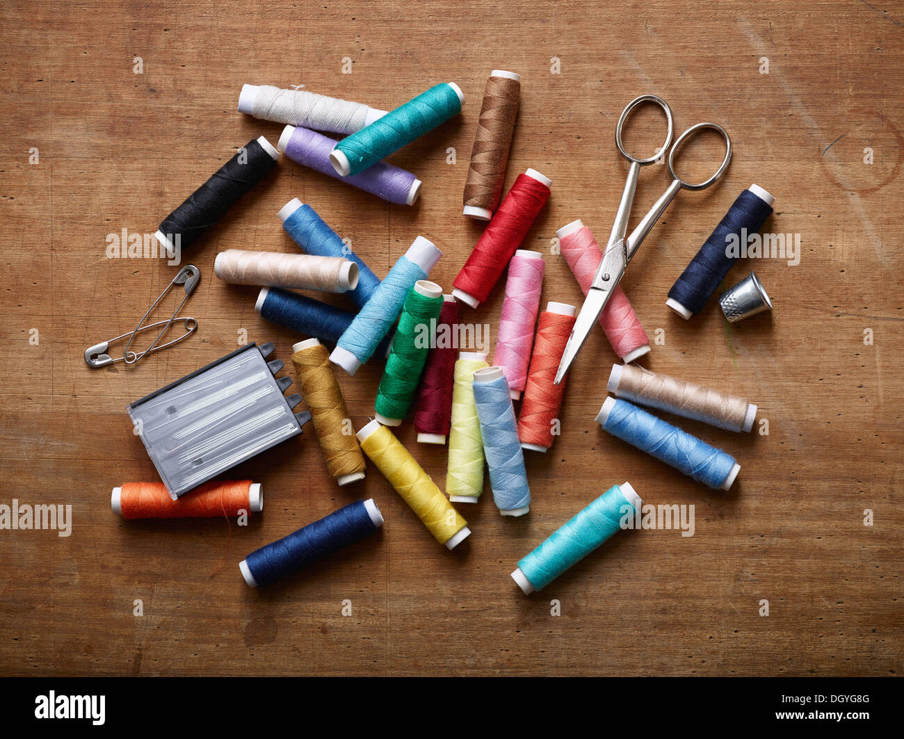 Various spools of colored thread in a pile with scissors, safety pins ...