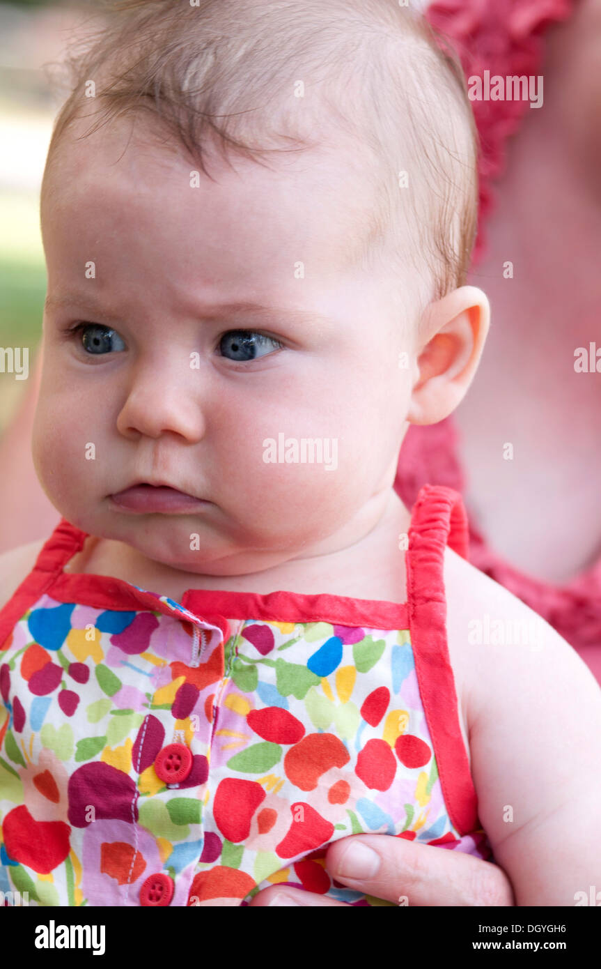 Close up portrait of a baby girl, outside being held and looking ...