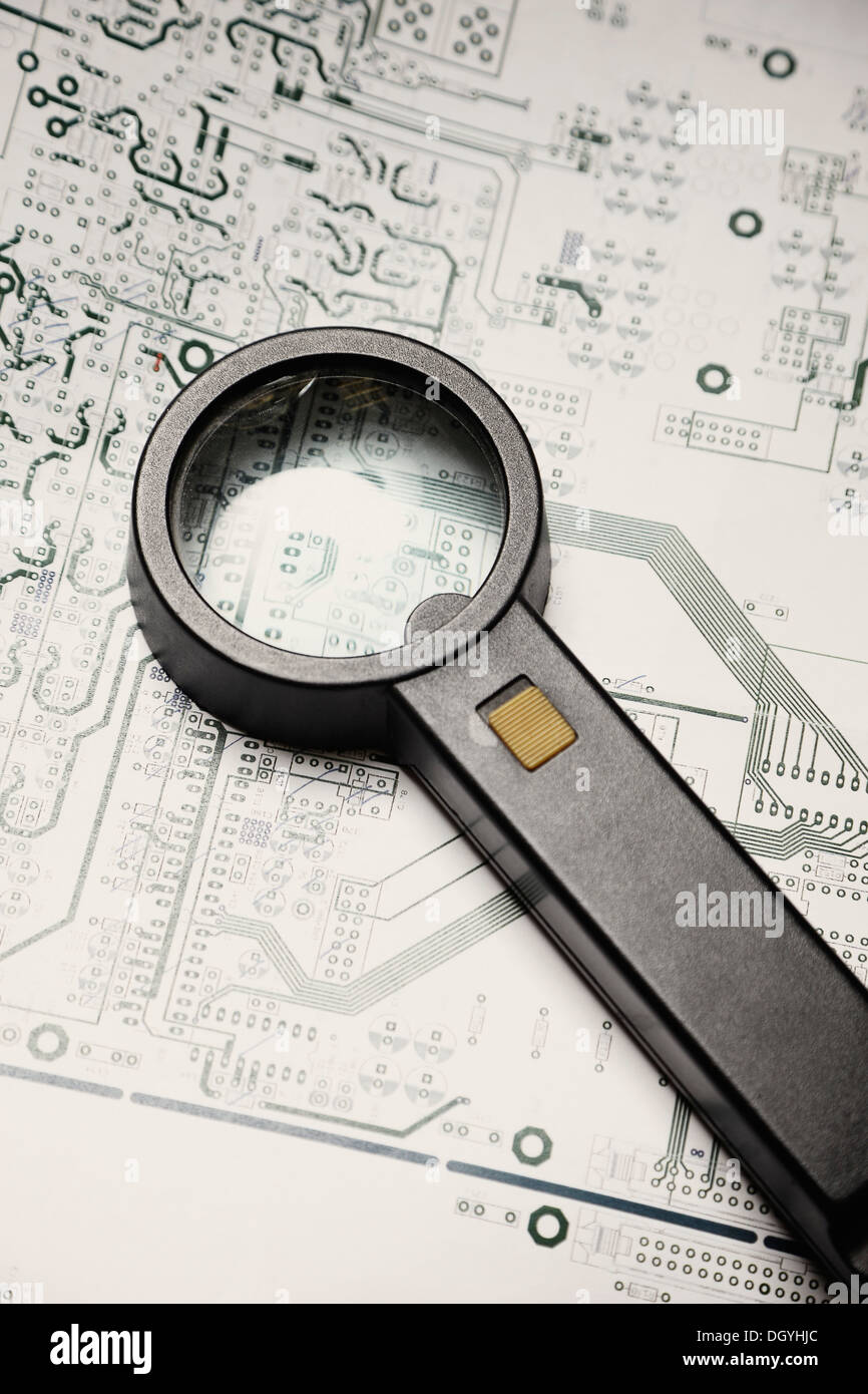 A magnifying glass lying on a schematic for a circuit board Stock Photo ...