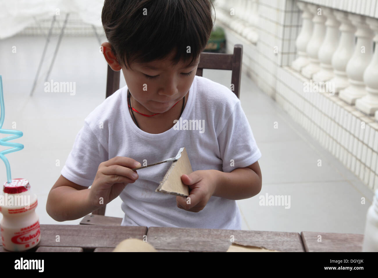 It's a photo of a little asian boy whi is doing DIY work with Cardboard ...