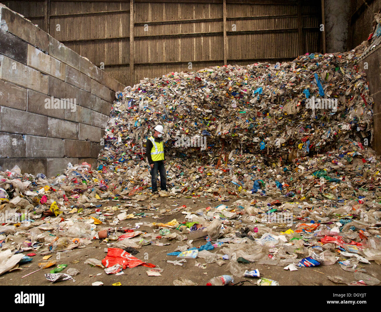 Man in recycling plant standing near large pile of plastic material ...
