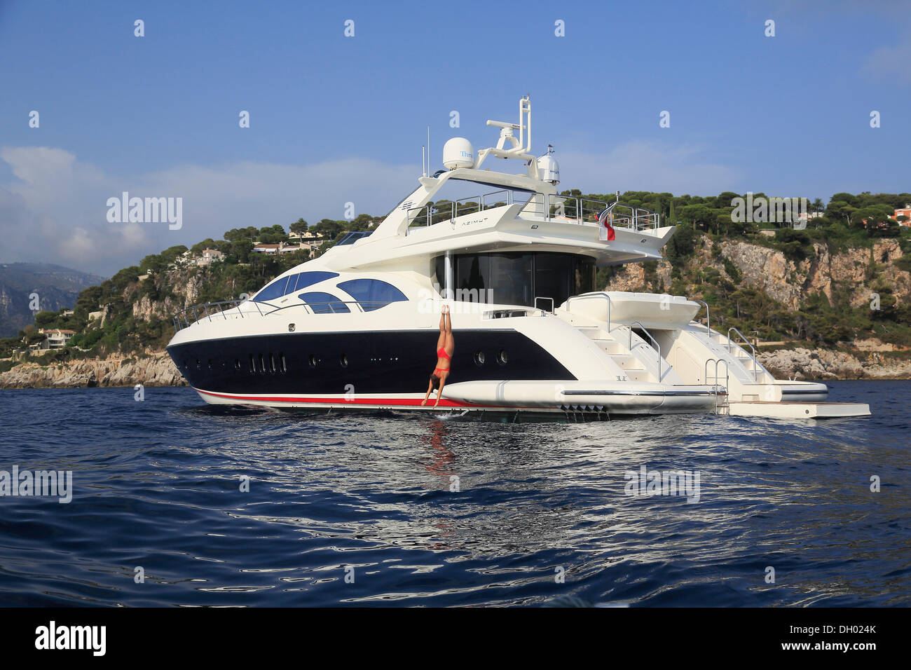 Young woman wearing a red swimsuit making a swan dive from the rear ...