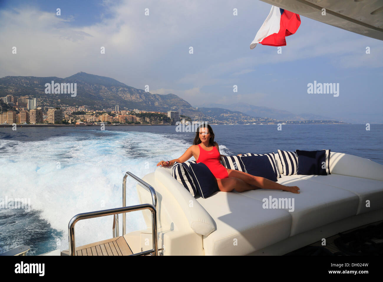 Young woman wearing a red swimsuit sitting on the back deck of a motor ...