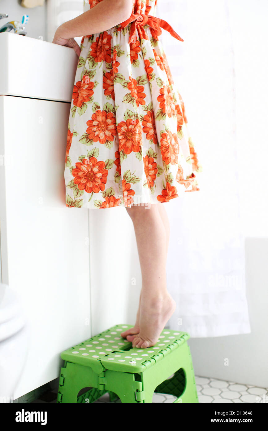 Mixed race girl standing on stool on tiptoe Stock Photo - Alamy
