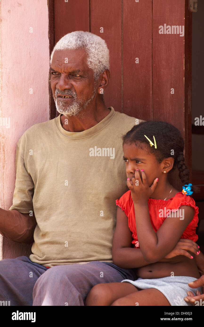 Daily life in Cuba - Afro-Caribbean man with young girl sat on steps in ...