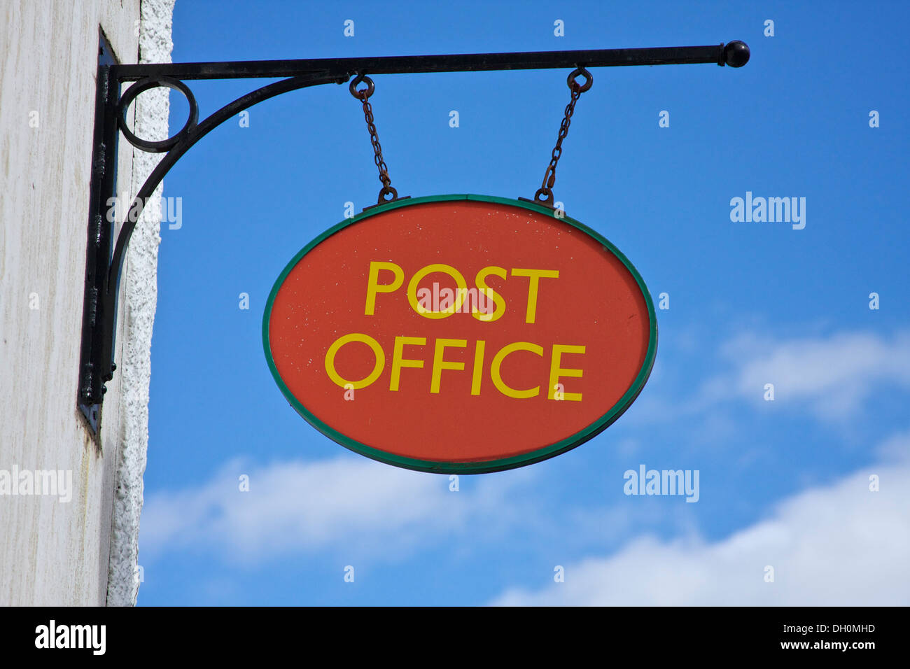 Bright red Post Office sign hanging against bright but cloudy blue sky ...