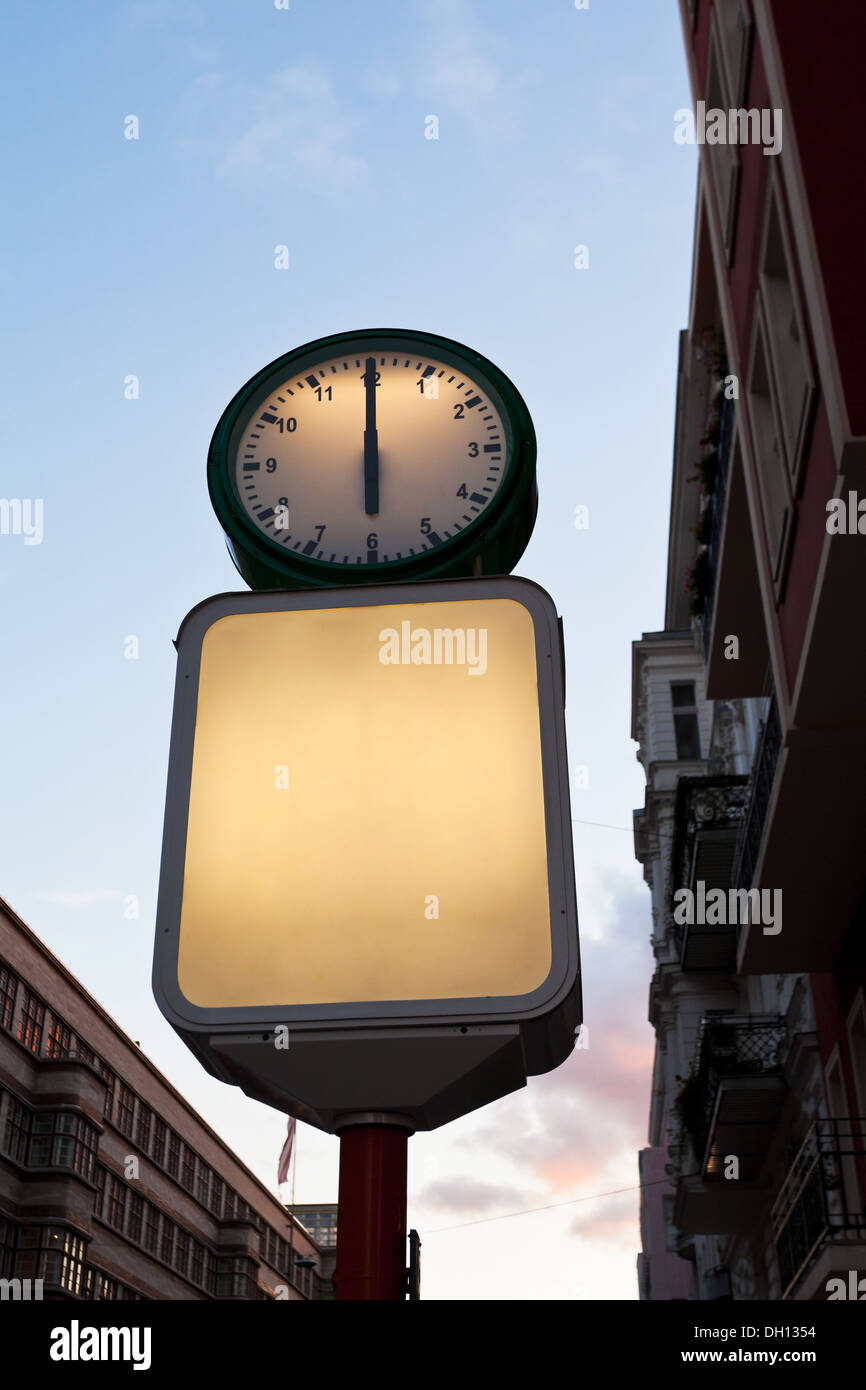 illuminated round street clock and blank advertising billboard in ...