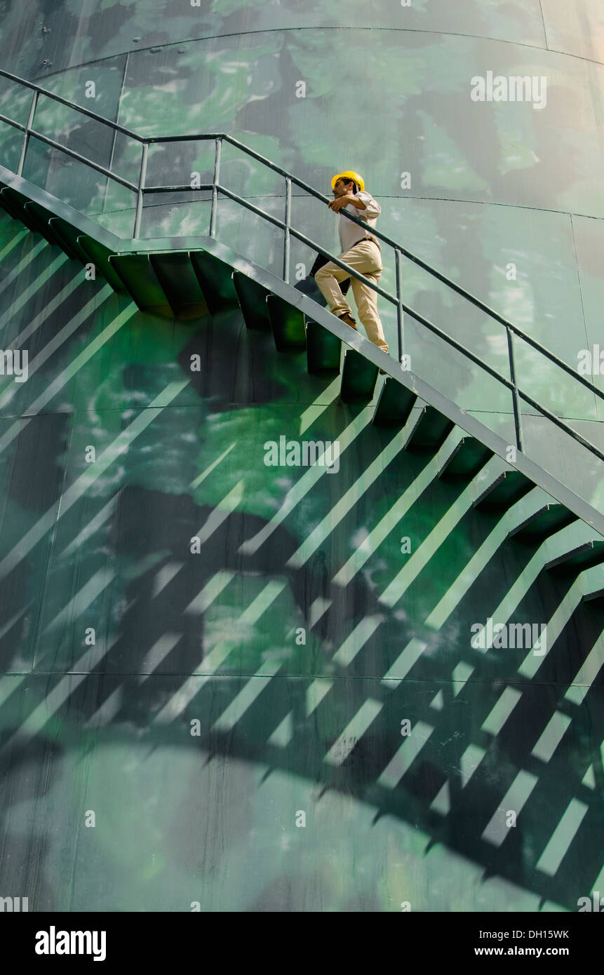 Hispanic worker climbing water tower Stock Photo - Alamy