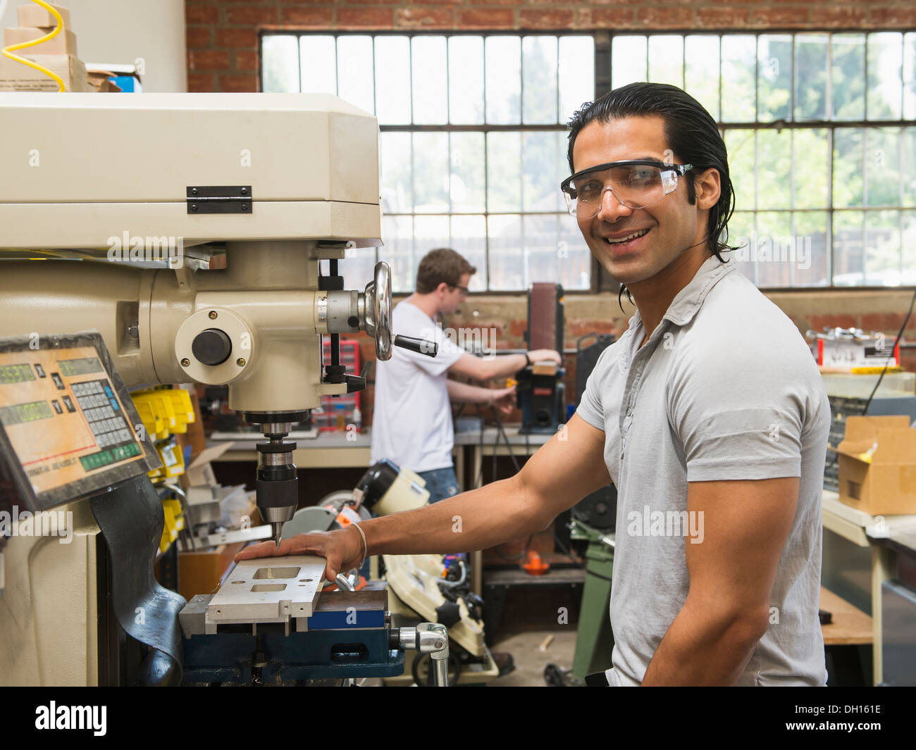 Workers using machinery in machine shop Stock Photo - Alamy