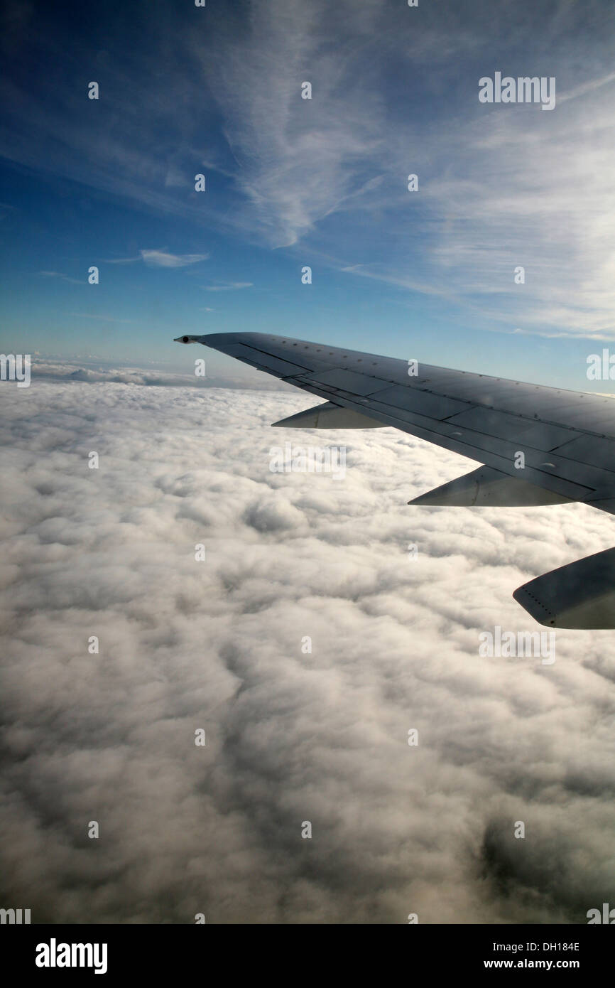 Looking out plane window at wing and clouds below Stock Photo - Alamy