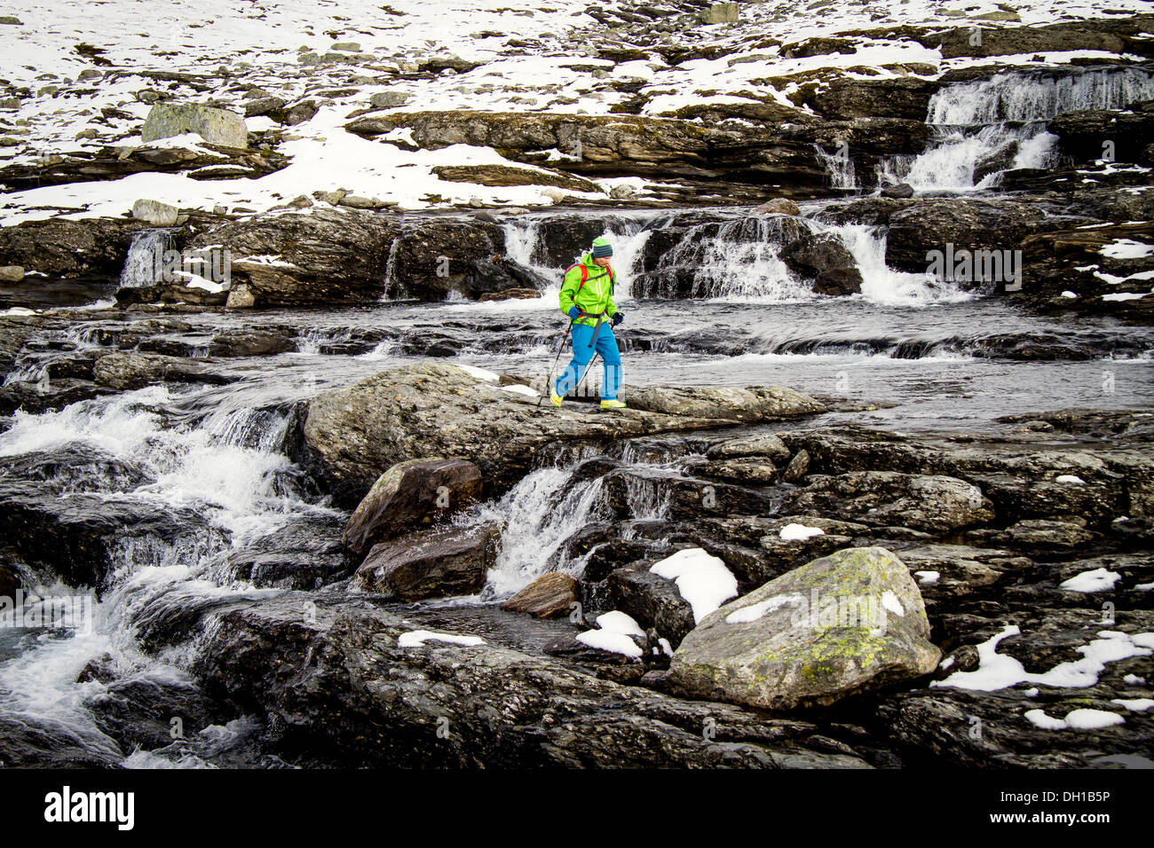 Man crosses mountain stream, water rushinng over rocks, Norway, Europe ...