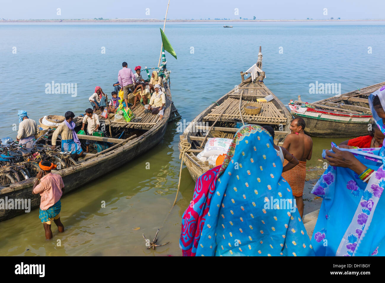 Passengers prepare to cross the Ganges river in a traditional wooden ...