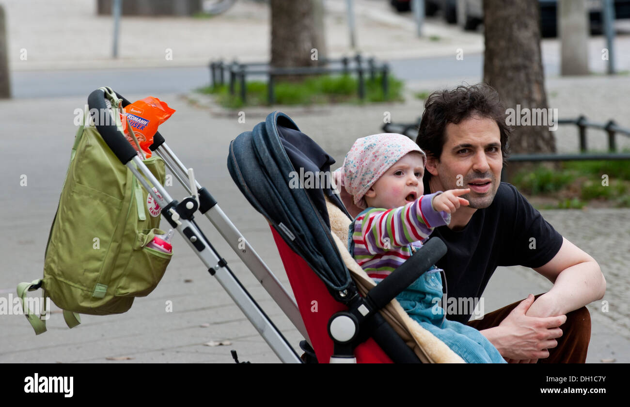 A child in a buggy notices something of interest with her father Stock ...
