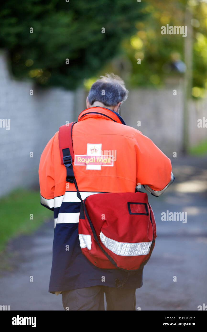 postman walking the street delivering mail Stock Photo - Alamy