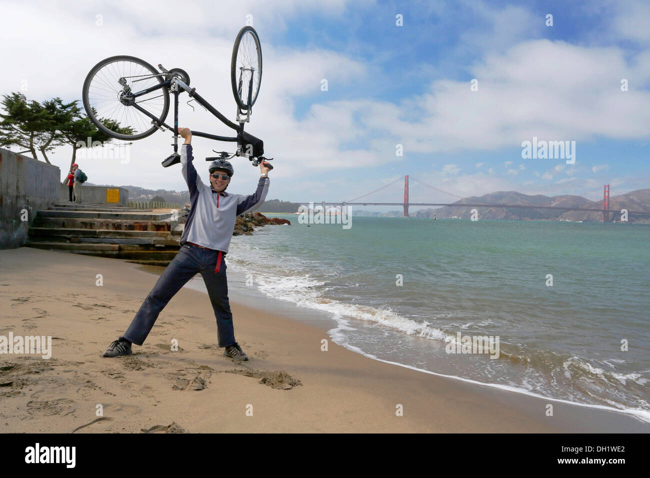 Cyclist holding his bike above his head, Golden Gate Bridge at the back ...