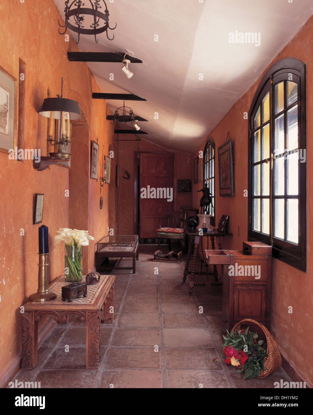 Stone tiled floor and low wood side tables in Spanish hall with ...