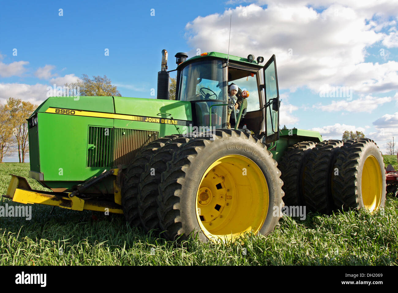 a young boy is leaning out the doorway of a large John Deere Triple ...