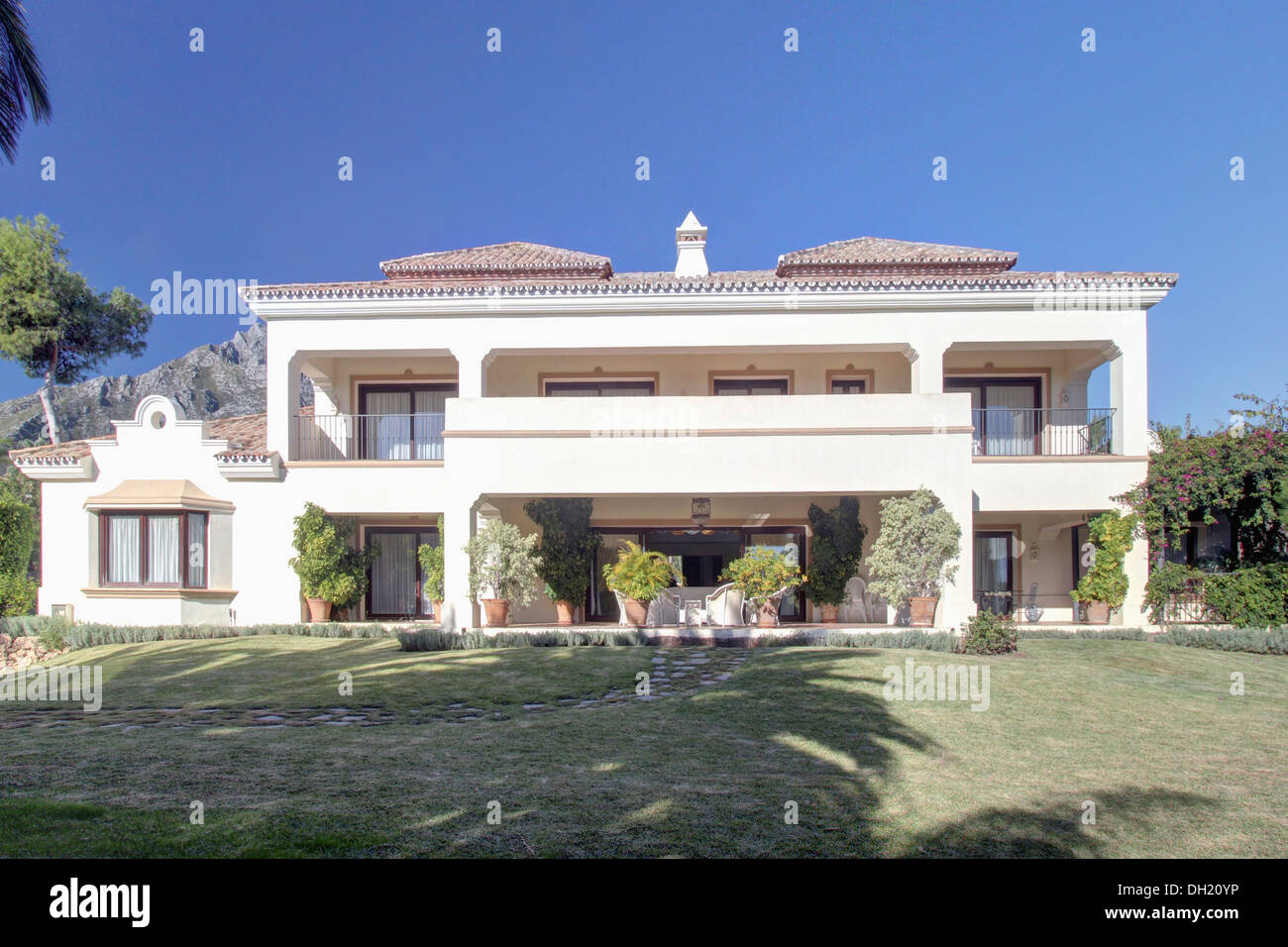 Pebbled path across lawn in front of large Spanish villa with spacious ...