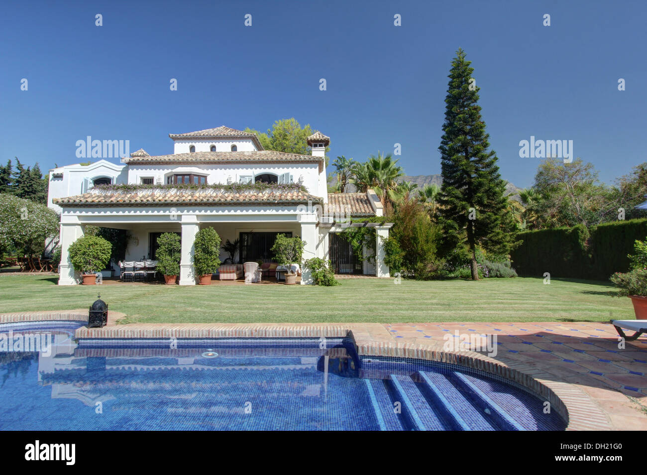 Blue swimming pool and lawn in grounds of large villa with spacious ...