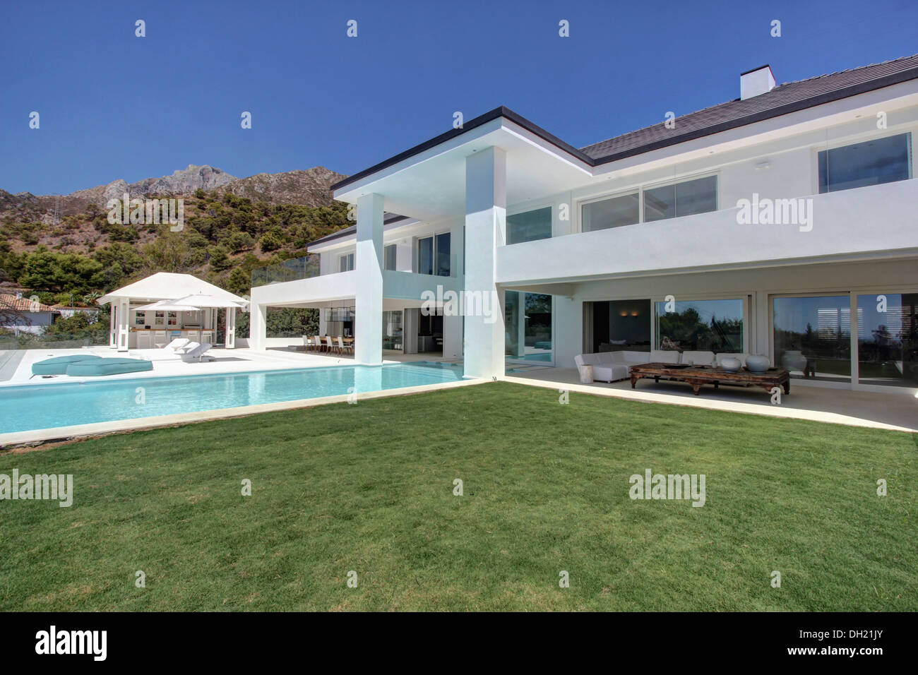 Large lawn and swimming pool in front of of large modern villa with ...