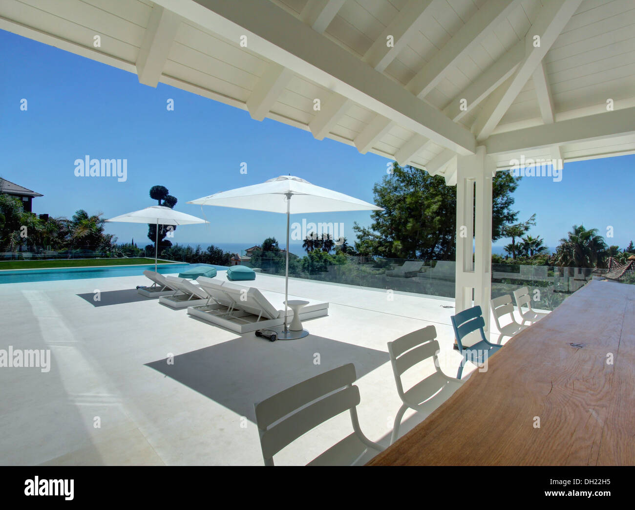 White chairs and plain wood on veranda of large modern Spanish villa ...