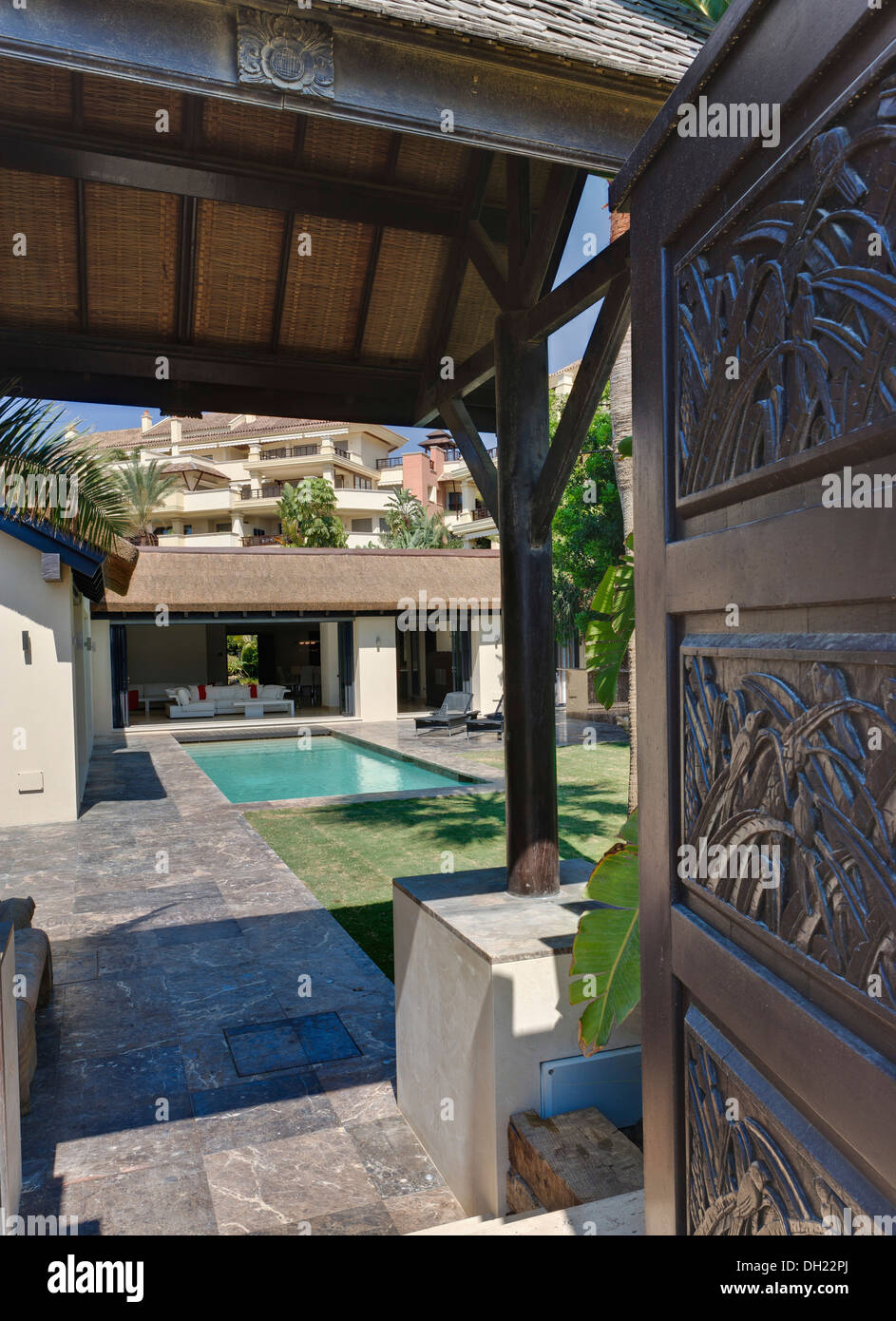 Carved wooden door open to courtyard garden of Spanish villa veranda ...