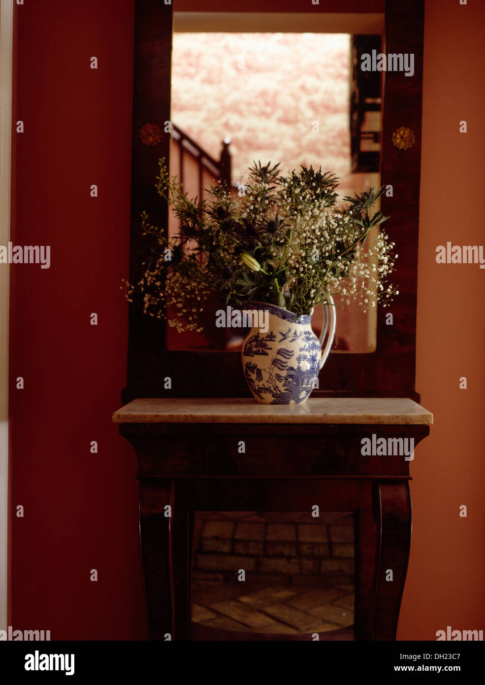 Mirror above blue+white Willow Pattern jug with summer flowers on small ...