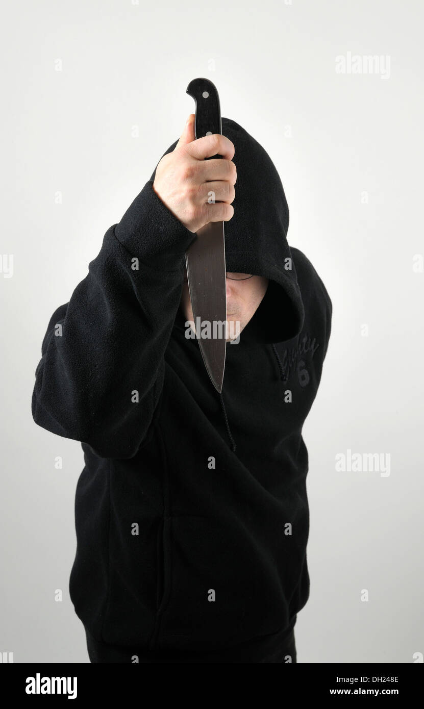 Man with a black hooded shirt and a raised knife Stock Photo - Alamy