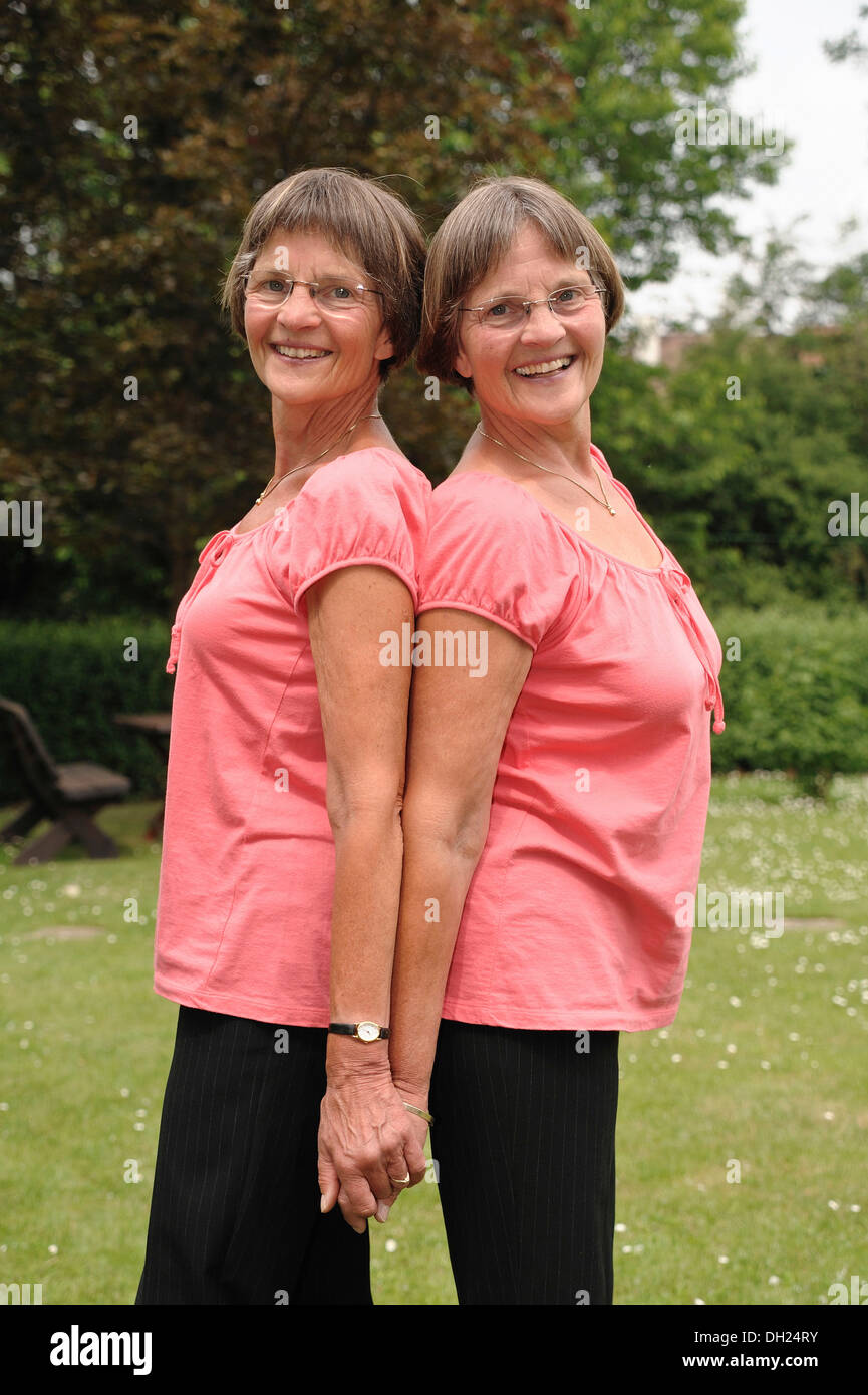 Two sprightly twin sisters standing back to back Stock Photo - Alamy