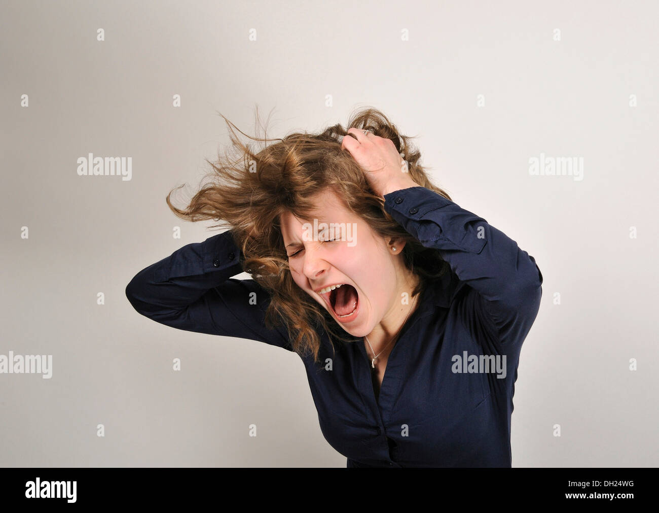 Young woman, 20, angry, screaming, holds her hands to her head and ...