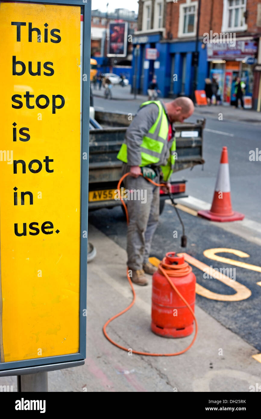 bus stop not in use sign road worker in background cones and bus stop ...