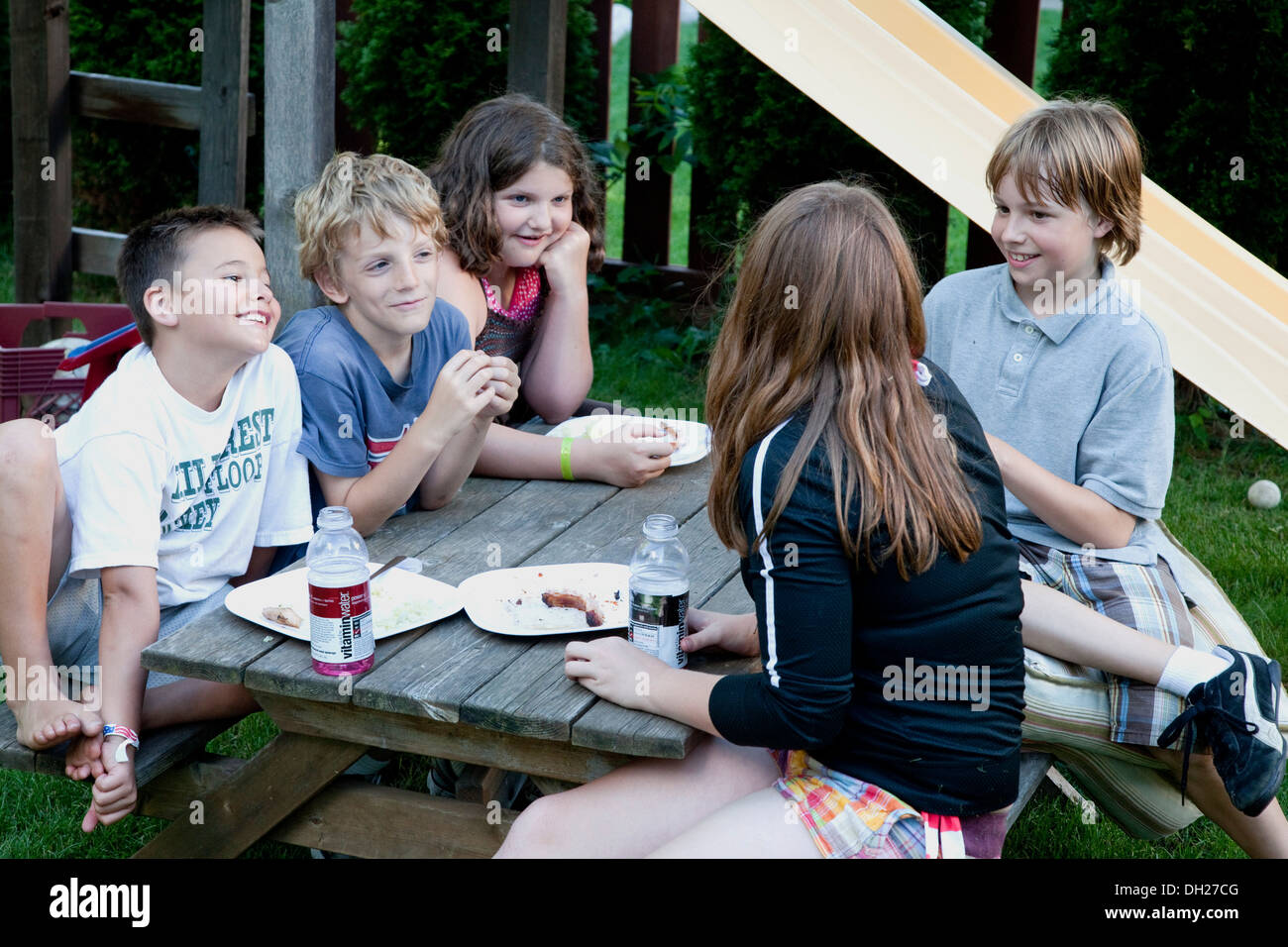 Kids having fun talking and eating at the children's picnic table. St ...